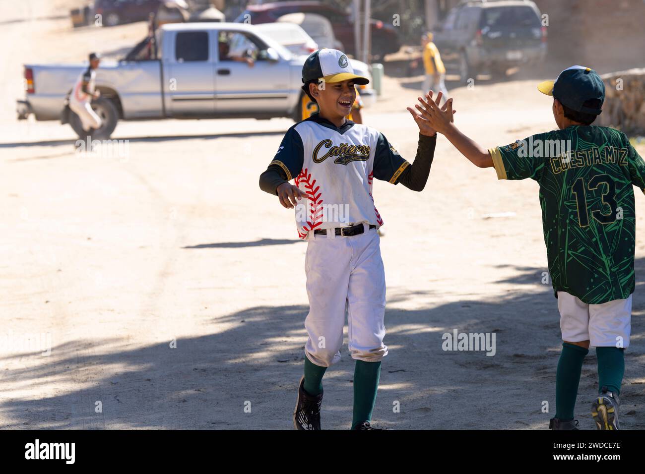 Boys play baseball in the dirt street in Todos Santos Baja Mexico. The ...