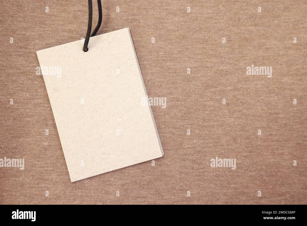 Cardboard tag on brown garment, top view. Space for text Stock Photo ...
