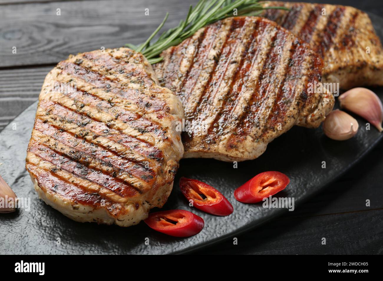 Delicious grilled pork steaks with spices on wooden table, closeup ...