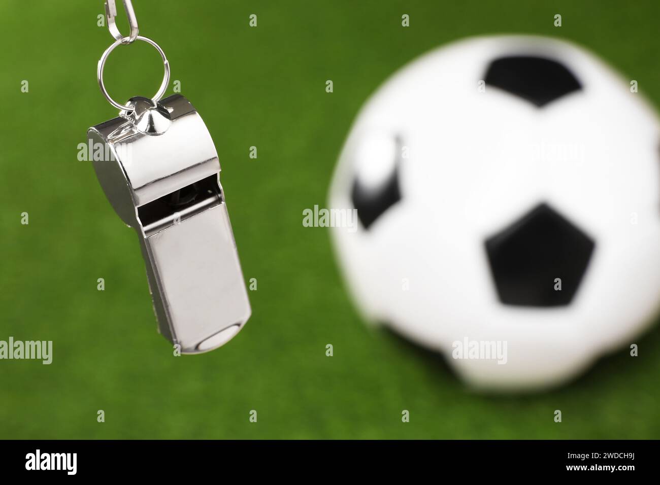 Football referee equipment. Metal whistle and soccer ball on green ...