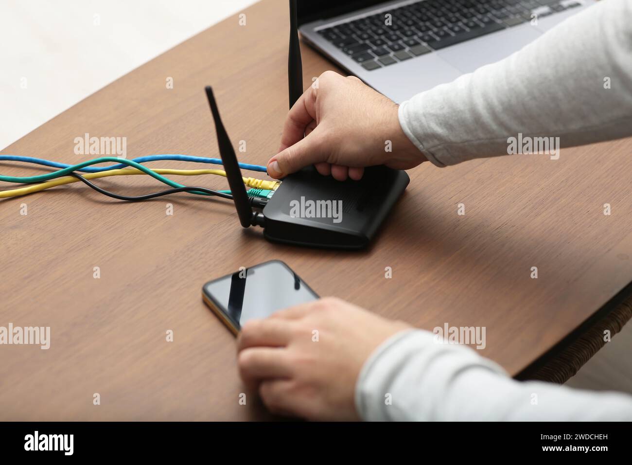 Man with smartphone connecting to internet via Wi-Fi router at wooden ...