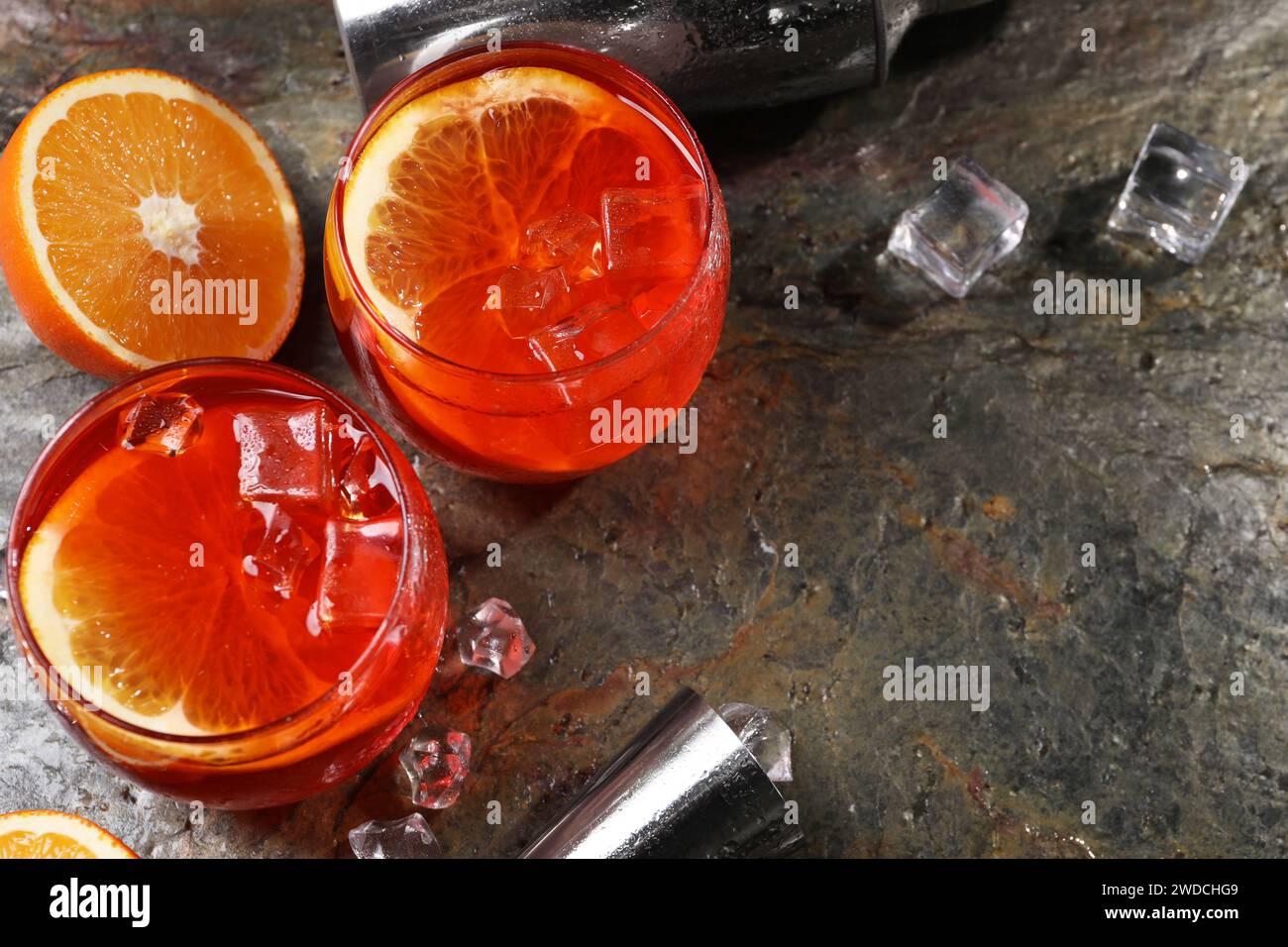 Aperol spritz cocktail, ice cubes and orange slices in glasses on grey ...