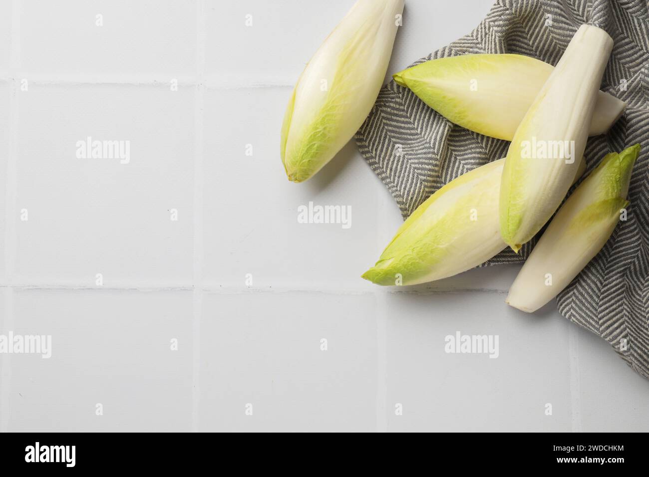 Fresh raw Belgian endives (chicory) on white tiled table, top view ...