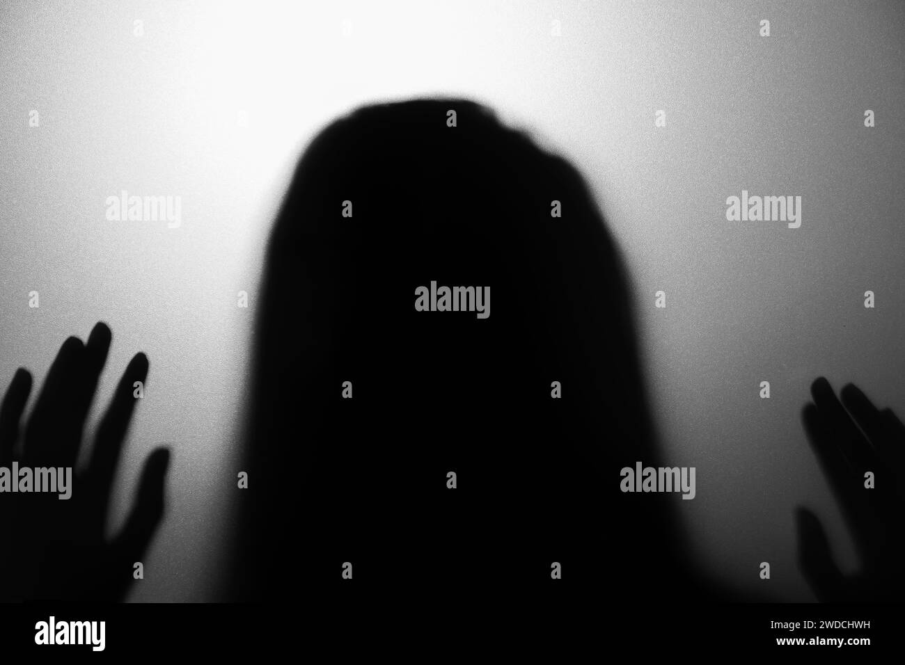 Silhouette Of Creepy Ghost Behind Glass Against Grey Background Stock