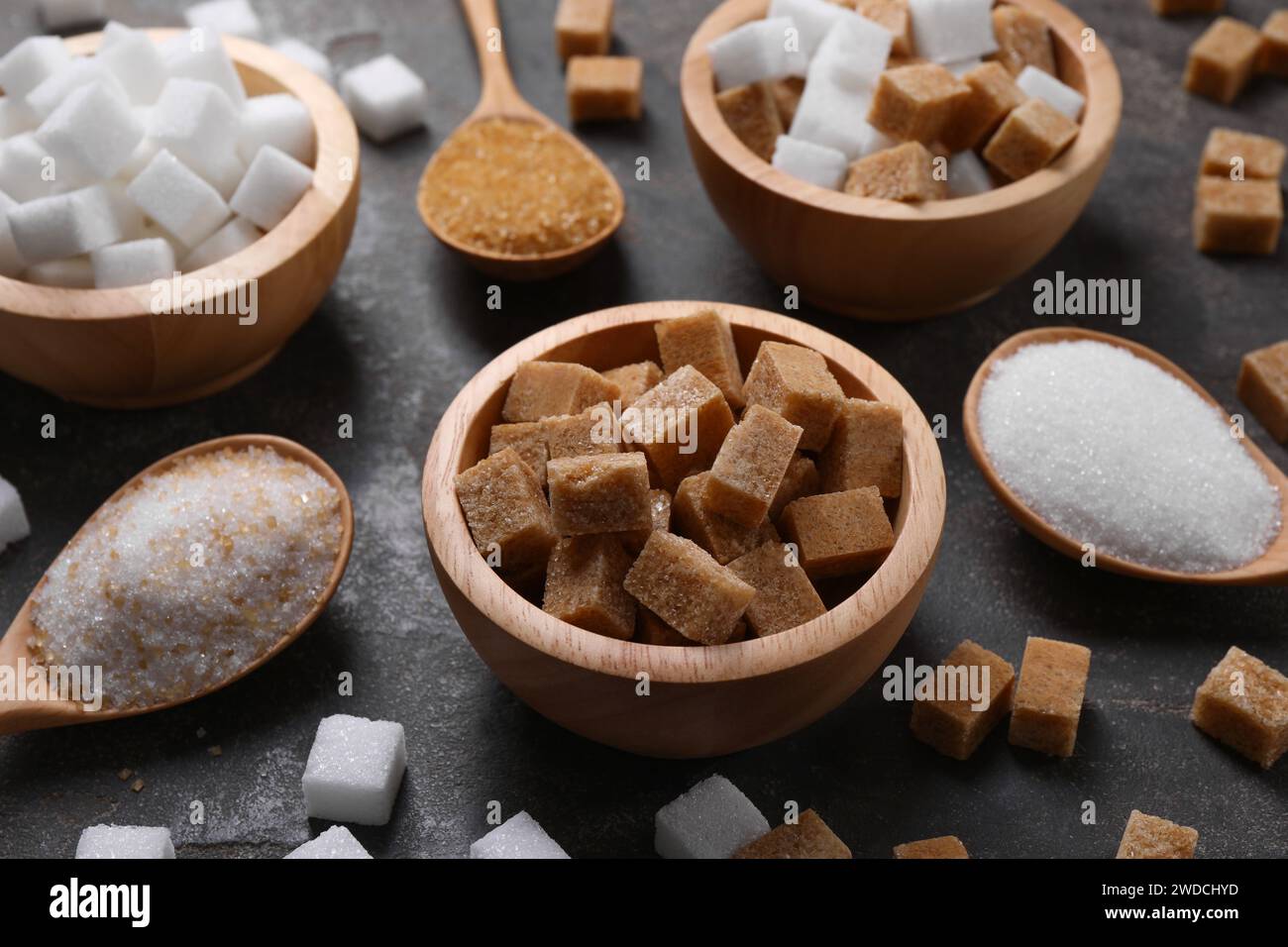 Bowls and spoons with different types of sugar on gray table Stock ...