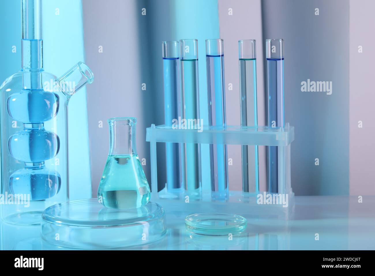 Laboratory analysis. Different glassware on table against color ...