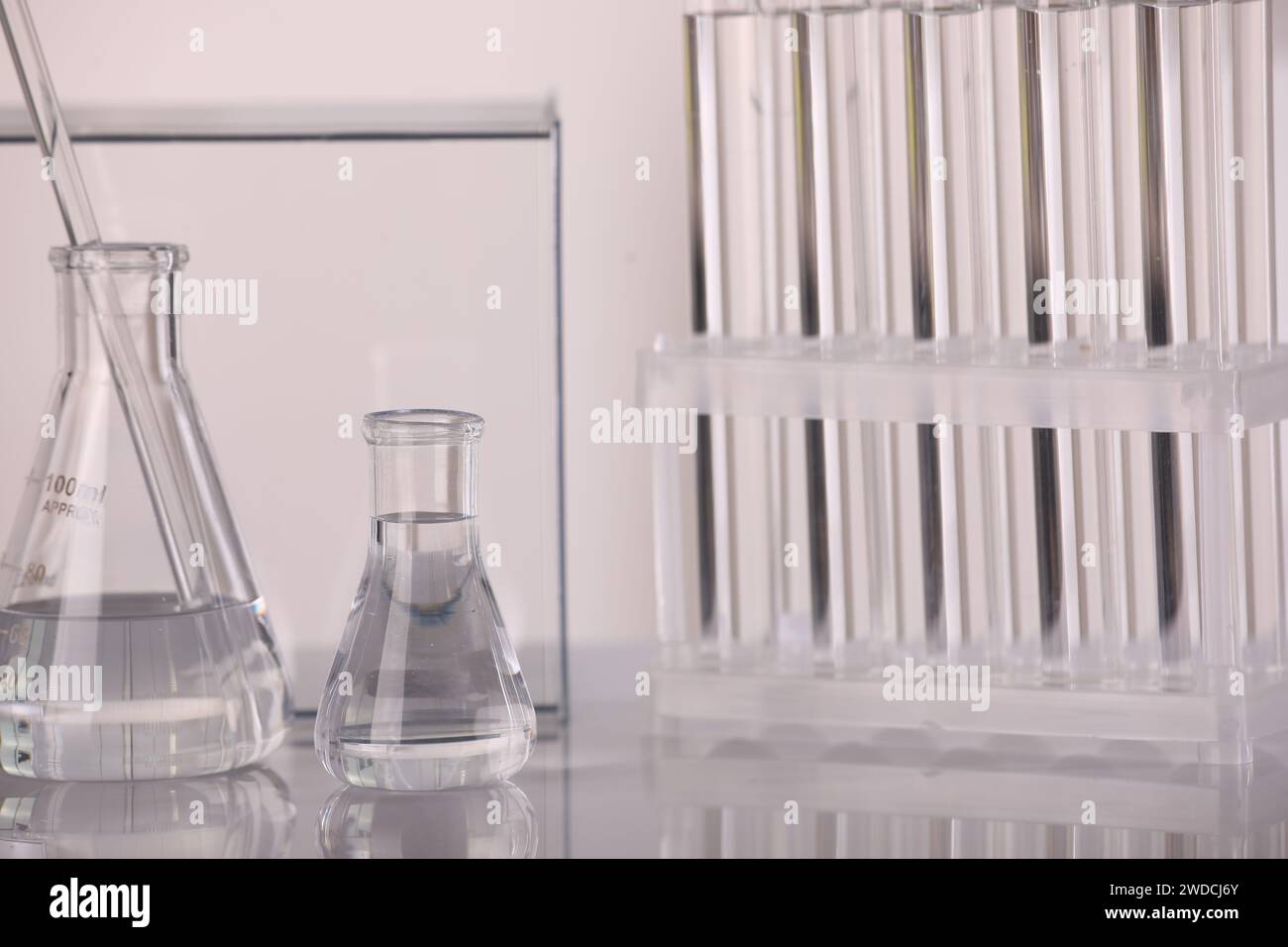 Laboratory analysis. Glass flasks and stirring rod on white table ...