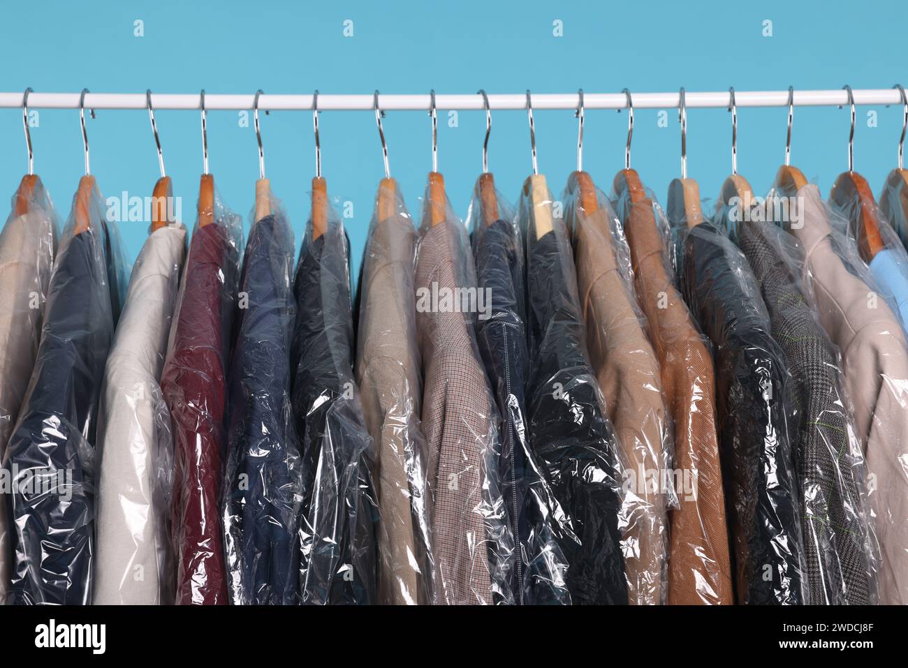 Dry-cleaning service. Many different clothes in plastic bags hanging on ...
