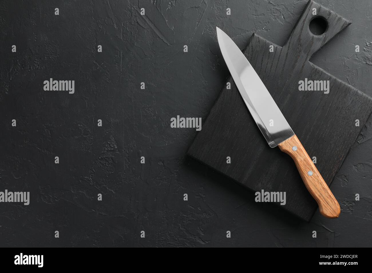 One sharp knife and board on dark textured table, top view. Space for ...