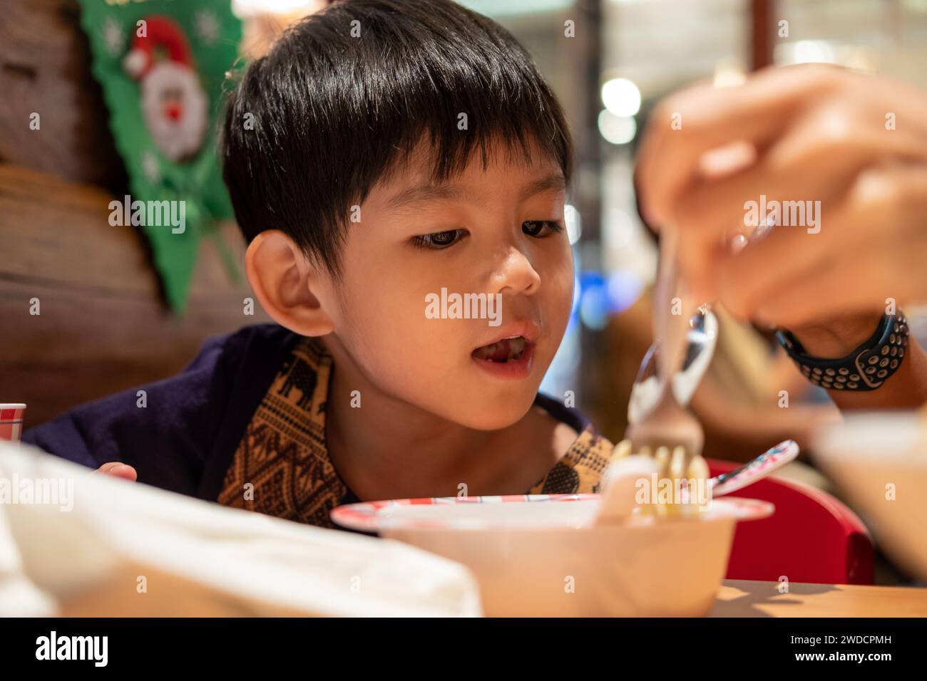 A little Asian boy is eating while his mother feeds him Stock Photo - Alamy