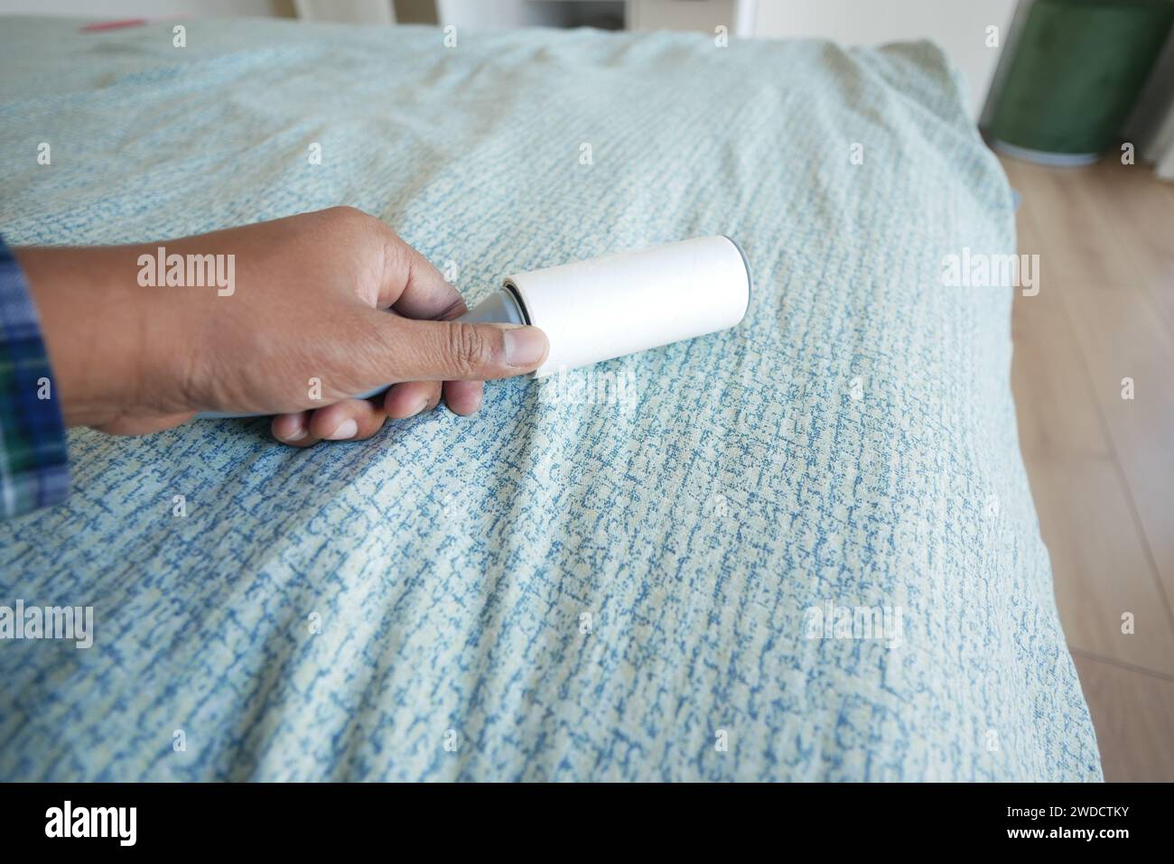 using an adhesive roller to remove lint and fluff from a bed Stock ...