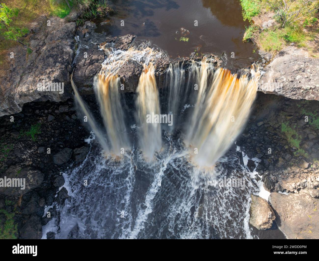 Aerial view of a waterfall tumbling over a rock ledge into a large open ...