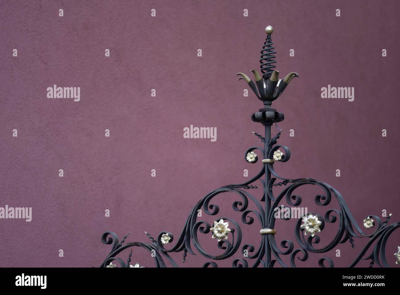 Vintage wrought iron entrance gate valance with golden rosettes against ...