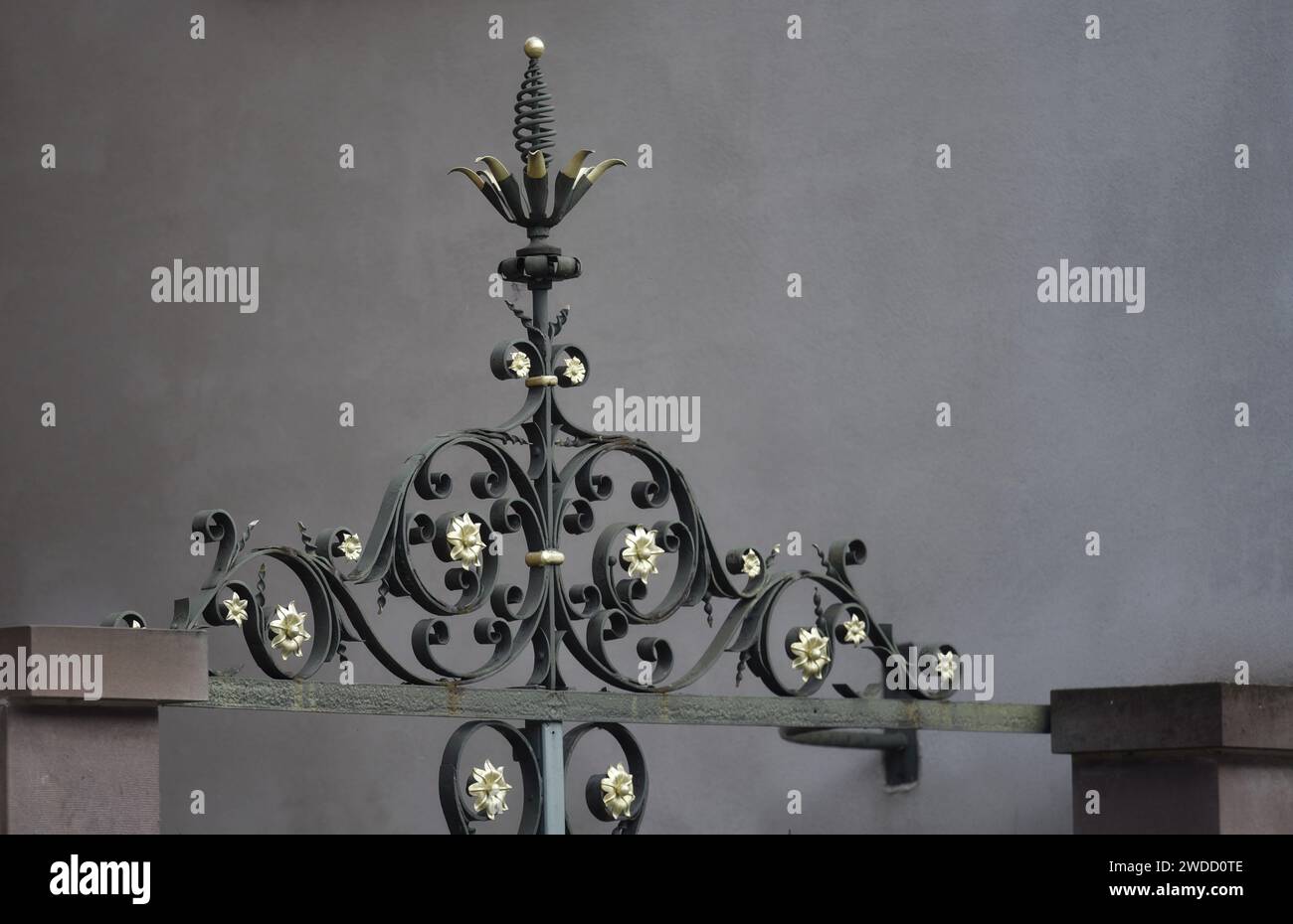 Vintage wrought iron entrance gate valance with golden rosettes against ...