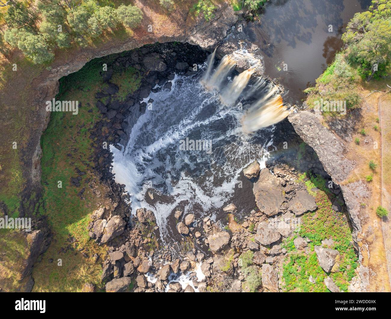 Aerial view of a waterfall tumbling over a rock ledge into a large open ...