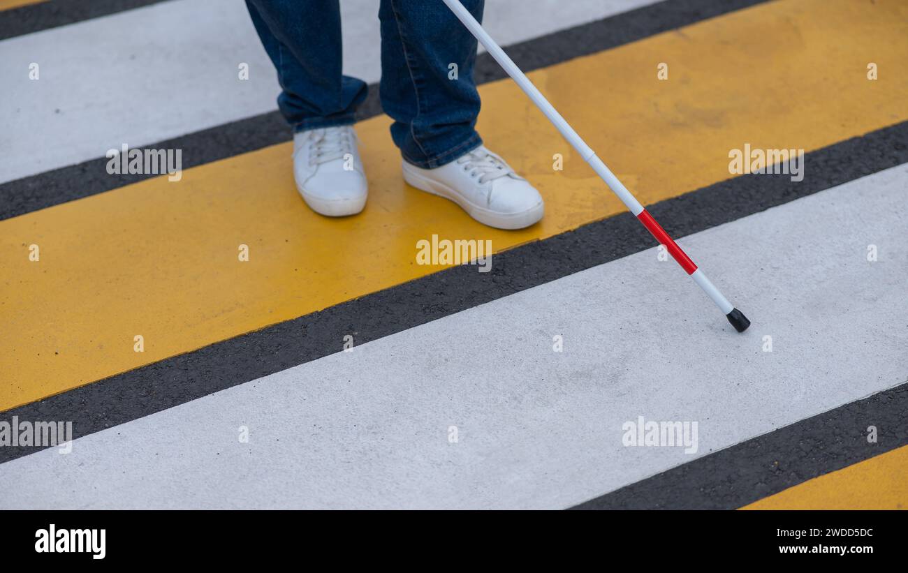 Close-up of the legs of a blind woman crossing the road at a crosswalk ...