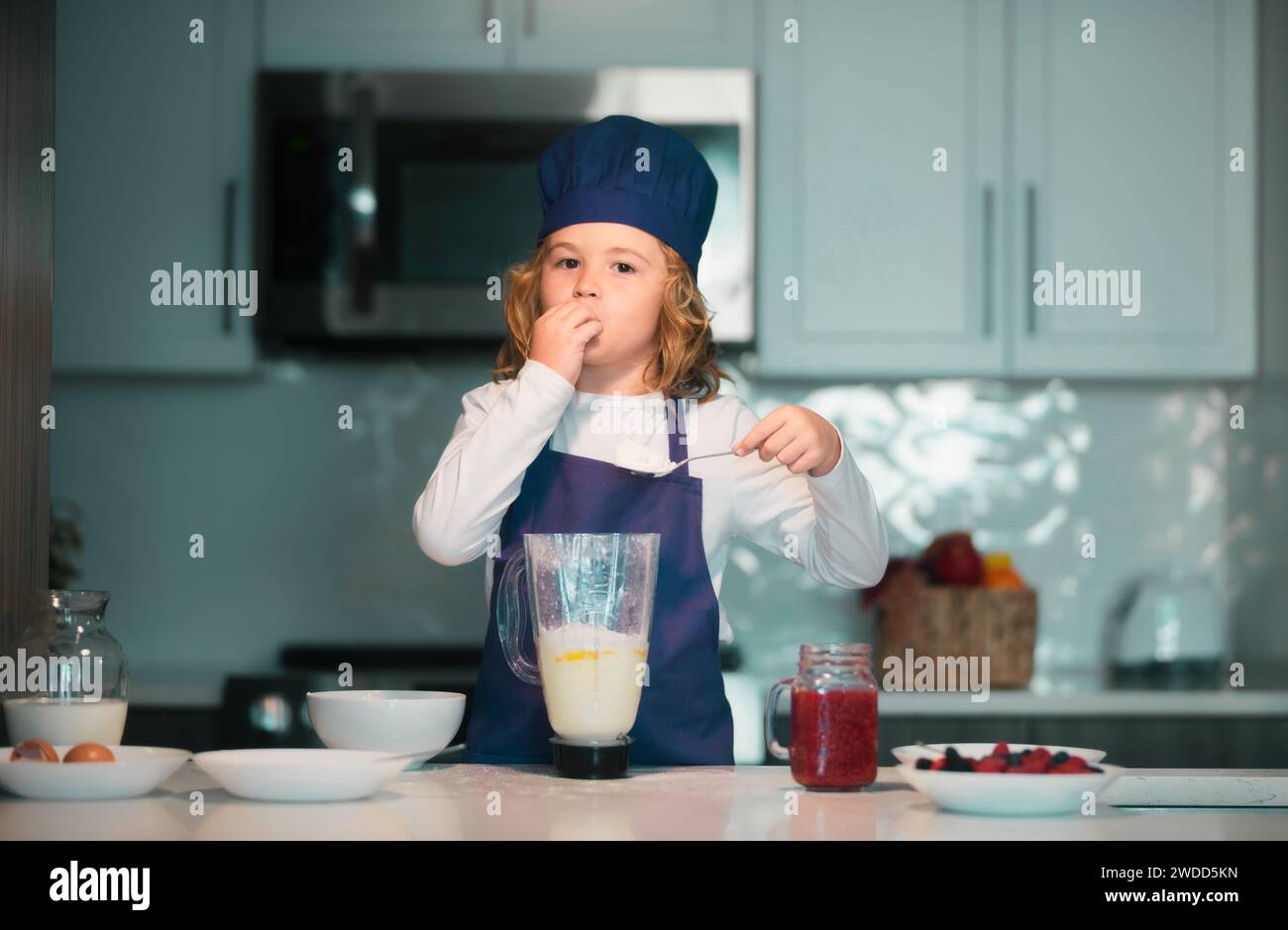 Child 7-8 years old in chef hat and apron. Child chef preparing healthy ...