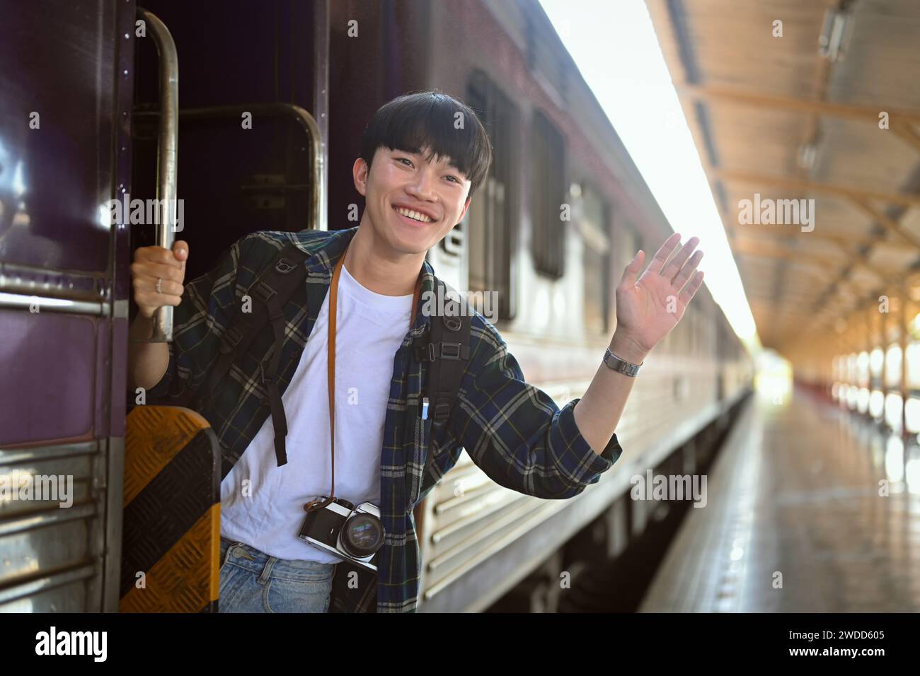 Happy young Asian man waving hand from the train while leaving the ...
