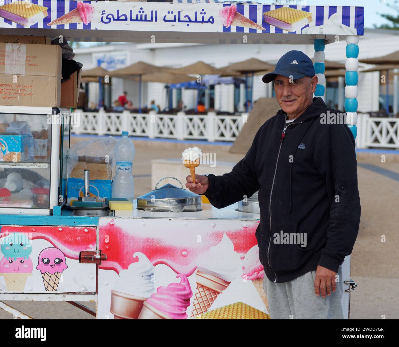Mobile ice cream salesman holds an ice cream and smiles in Essaouira ...