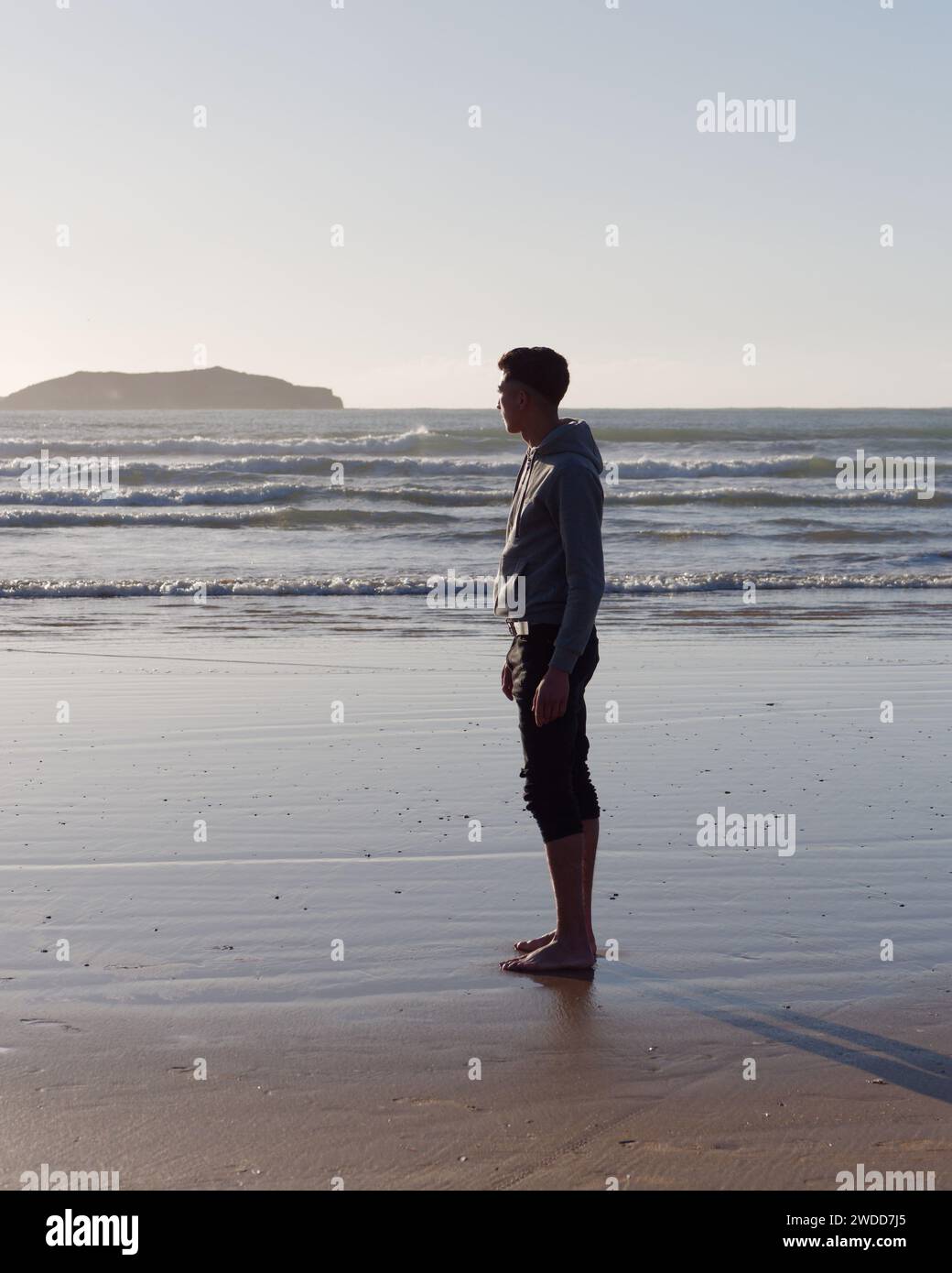 Handsome young man in profile standing on a beach in Essaouira, Morocco ...