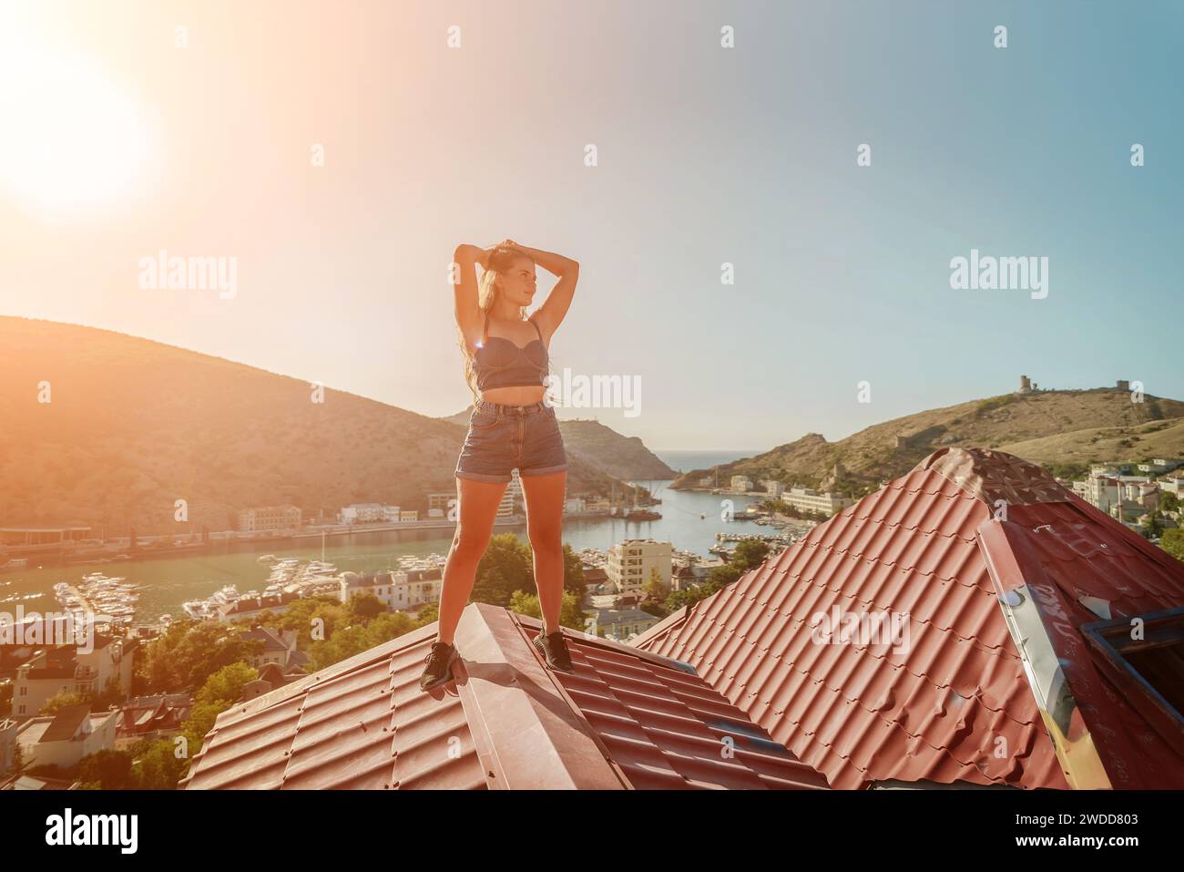 Woman standing on rooftop, enjoys town view and sea mountains. Peaceful ...