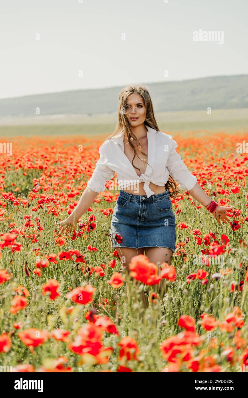 Happy woman in a poppy field in a white shirt and denim skirt with a ...