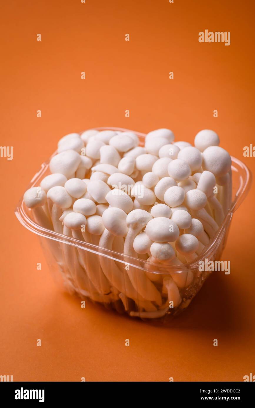Small white edible beech mushrooms with salt and spices on a plain ...