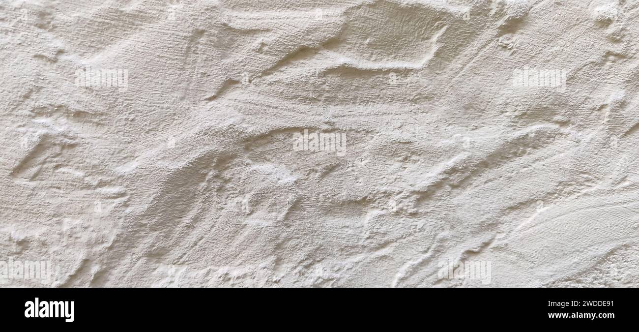 The rough texture of a poorly plastered light-colored wall. An uneven ...