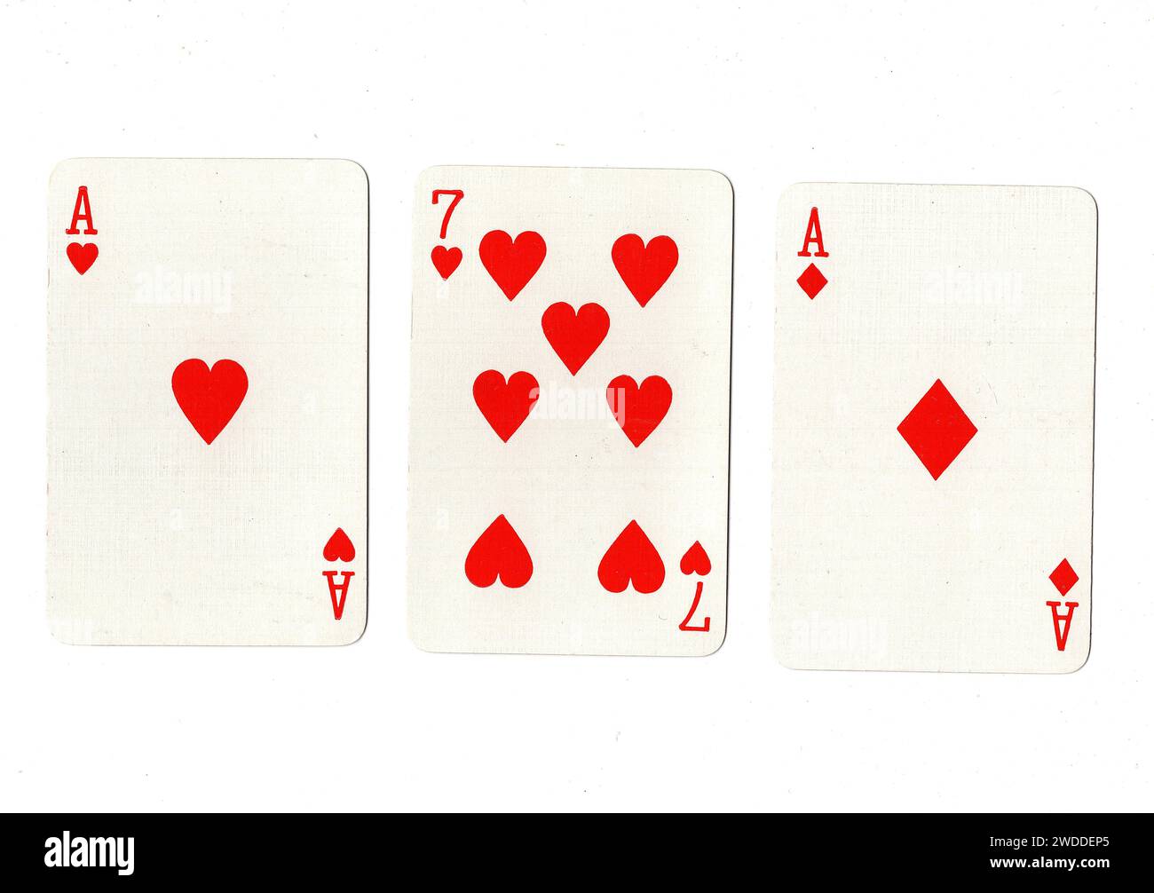 Vintage playing cards showing a pair of red aces and a red seven ...