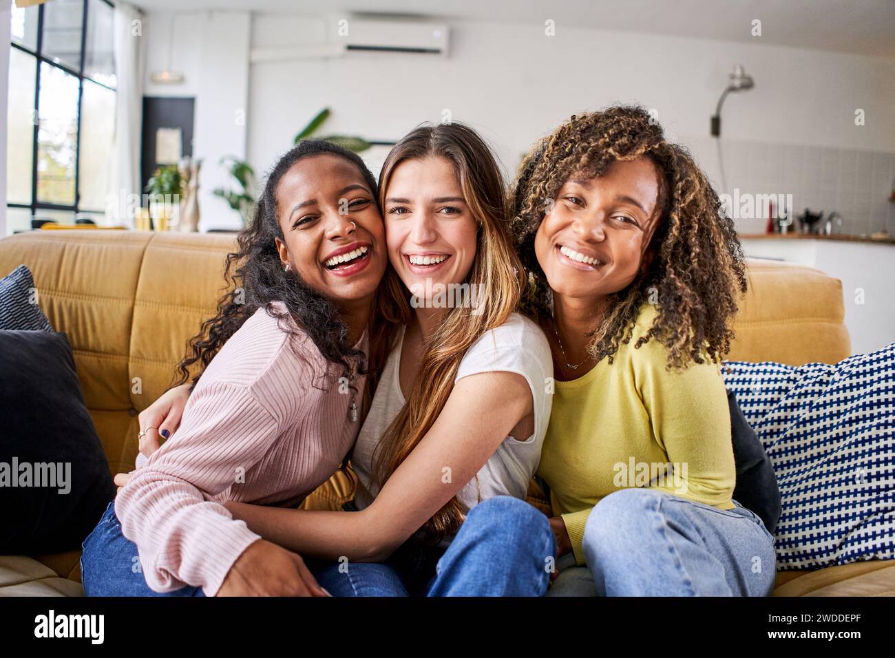 Portrait three attractive female room mates looking smiling at camera ...