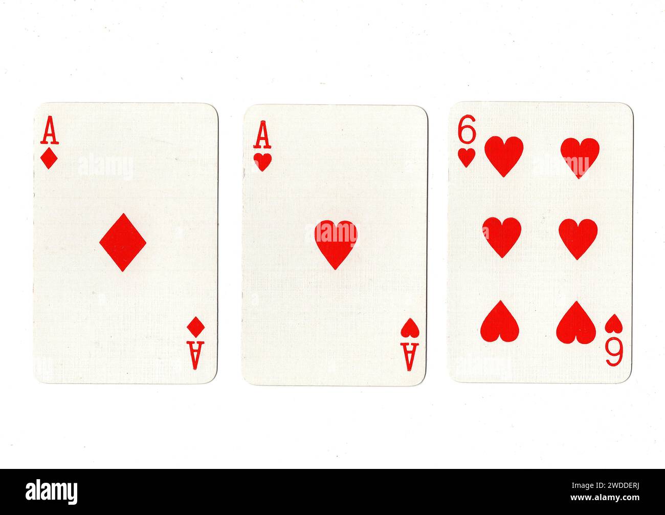Vintage playing cards showing a pair of red aces and a red six isolated ...