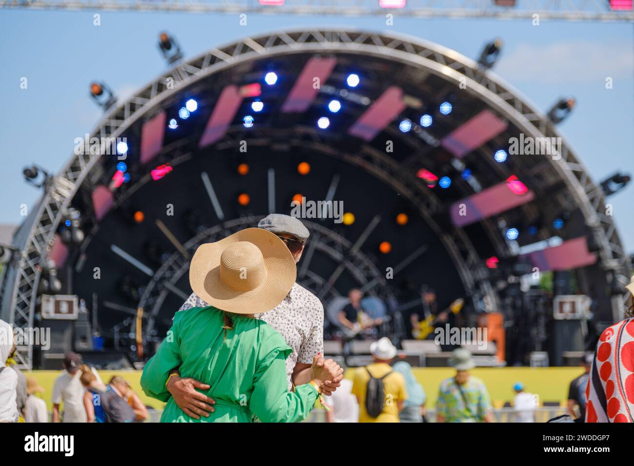 Couple dancing at an outdoor music festival with a live band performing ...