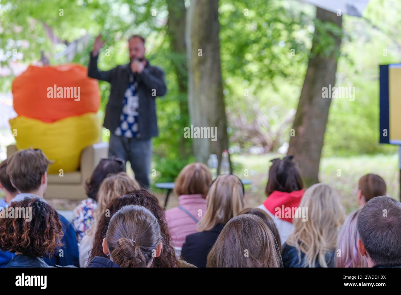 An inspiring public speaker addresses a seated crowd at an outdoor ...