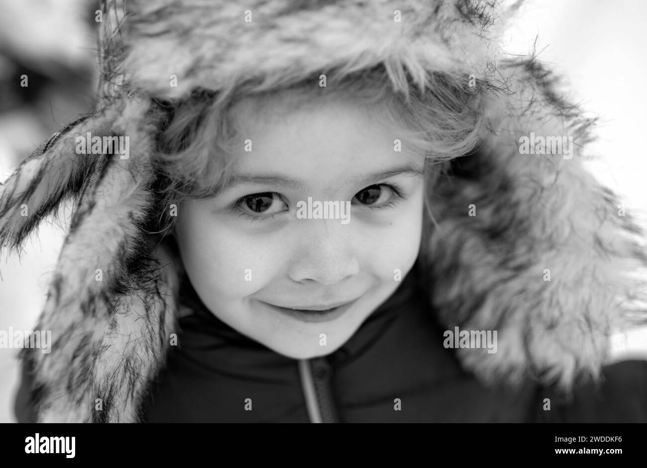 Winter child face close up. Happy child playing with snow on a snowy ...