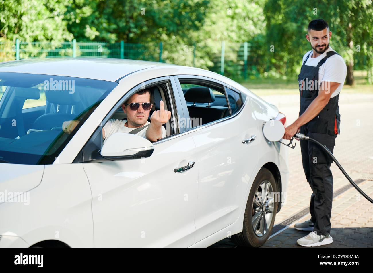 Rude driver showing middle finger to other car on gas station. Angry ...