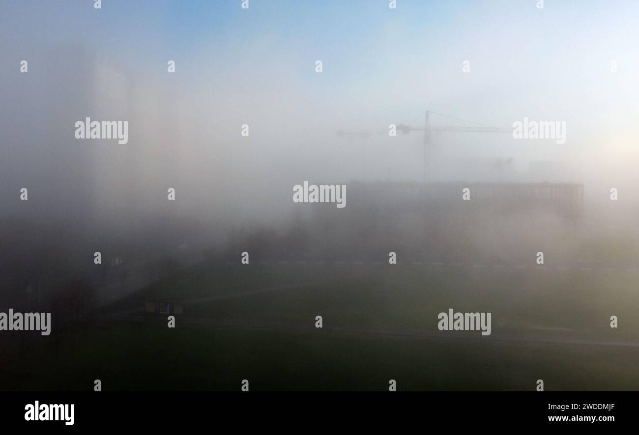 Construction cranes and a multi-storey residential building, shrouded ...