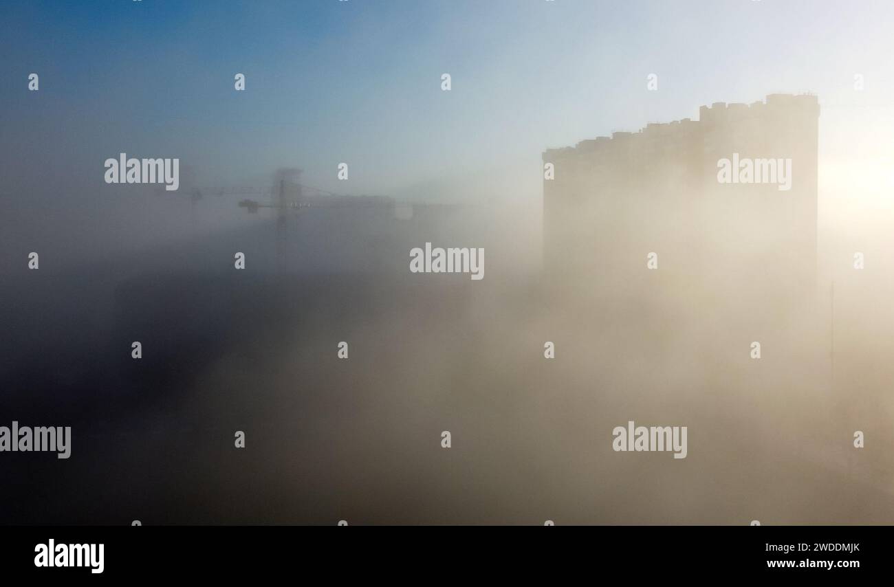Construction cranes and a multi-storey residential building, shrouded ...