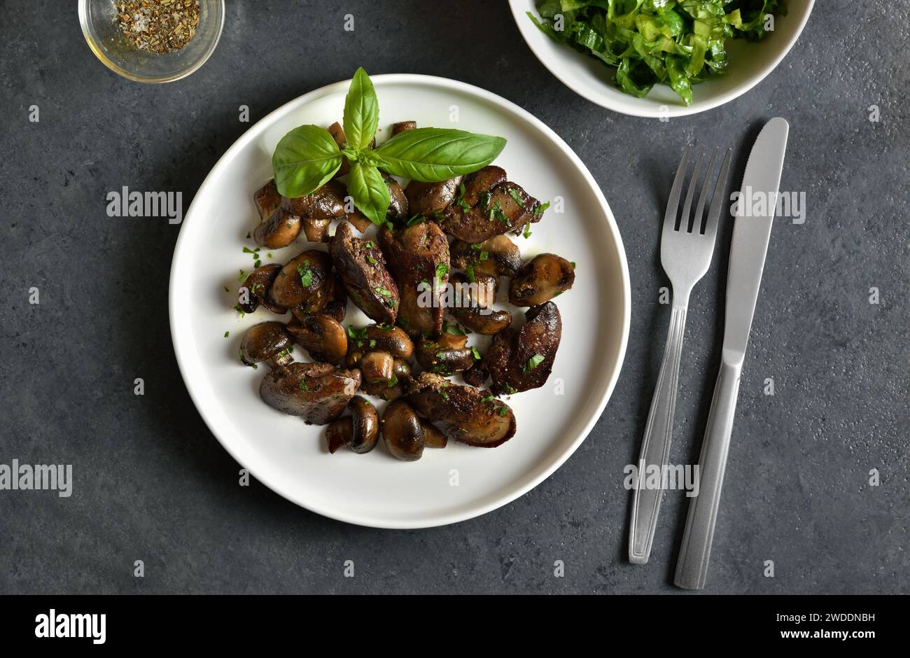 Roasted chicken liver with mushrooms on white plate over dark stone ...