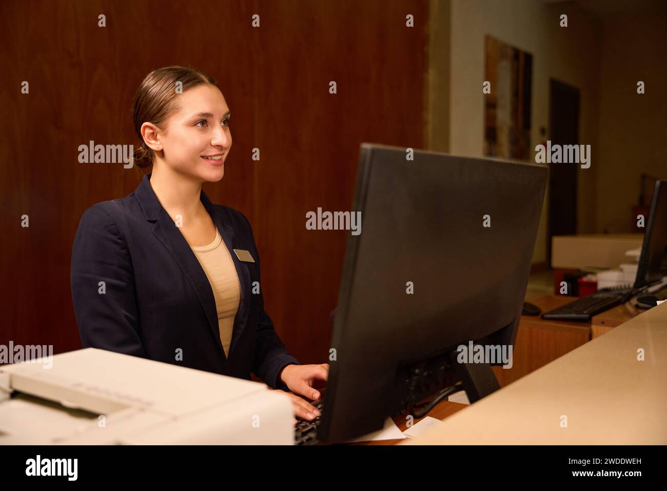 Welcoming female administrator standing at reception desk Stock Photo ...
