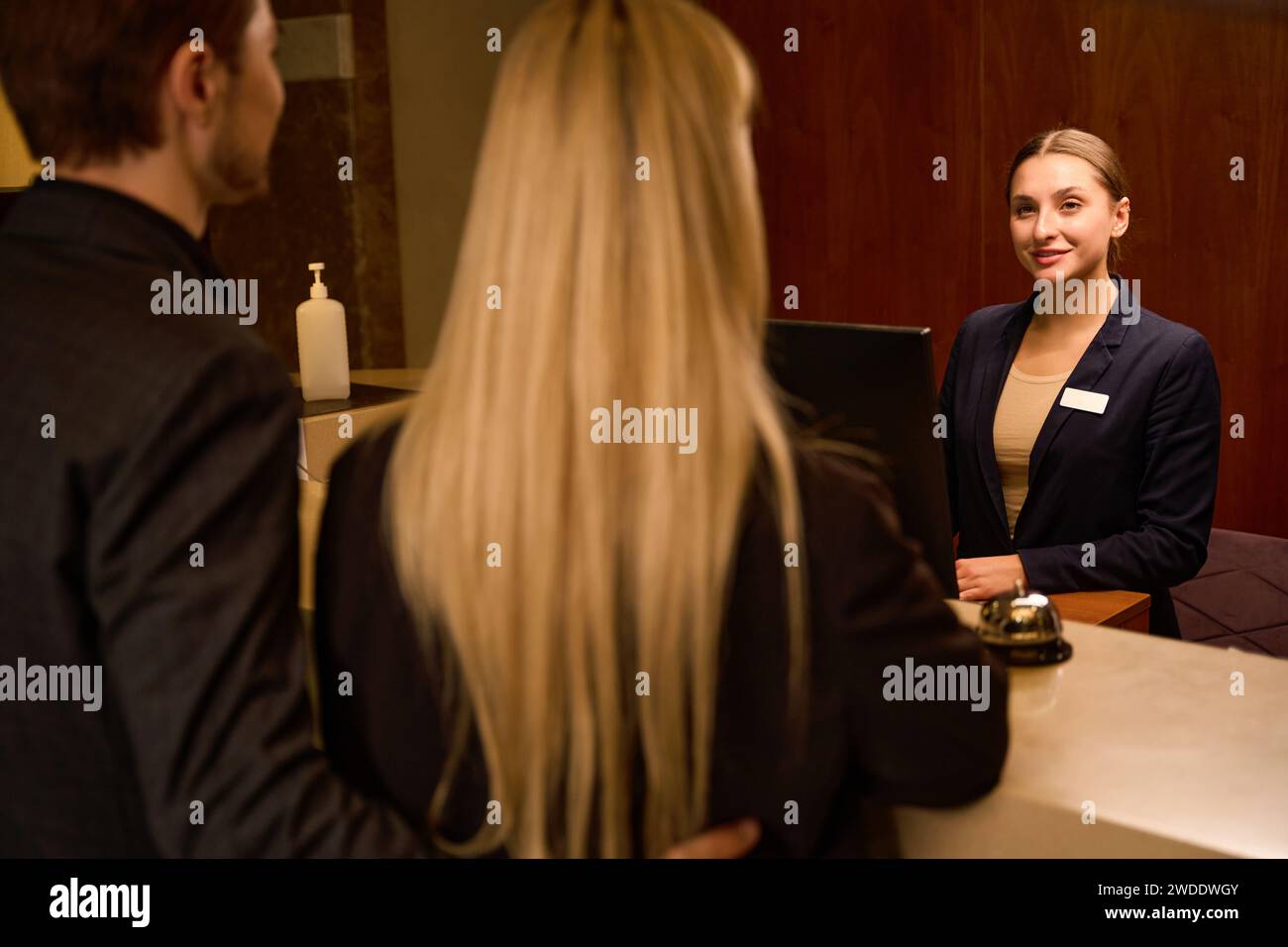 Smiling receptionist greeting young couple at reception desk Stock ...