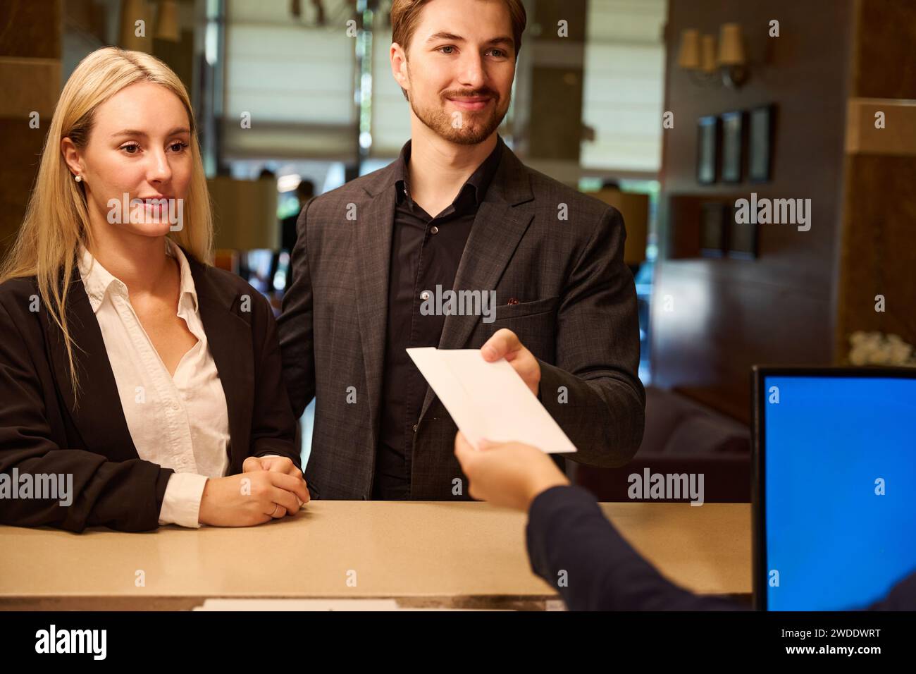 Young couple getting paper envelope from receptionist hand Stock Photo ...