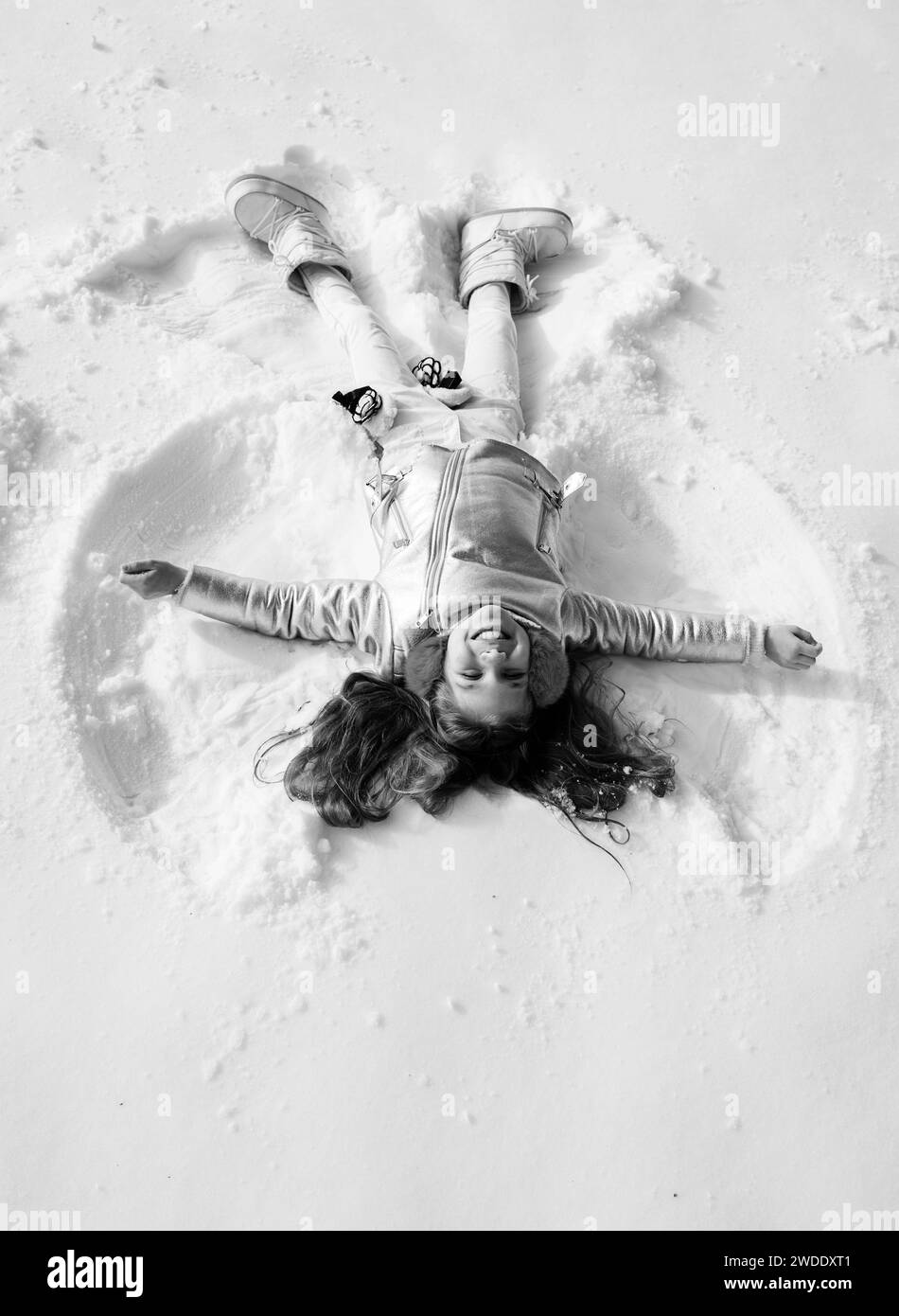 Snow angel made by a kid in the snow. Child girl playing and making a ...