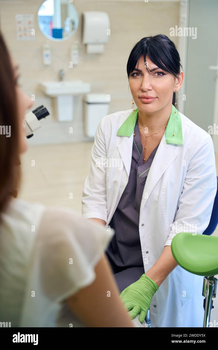 Female gynecologist looking at camera while examining partial pregnant ...