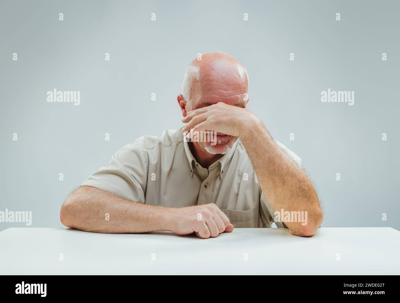 Seated elder with hand over face shows visible signs of distress or ...