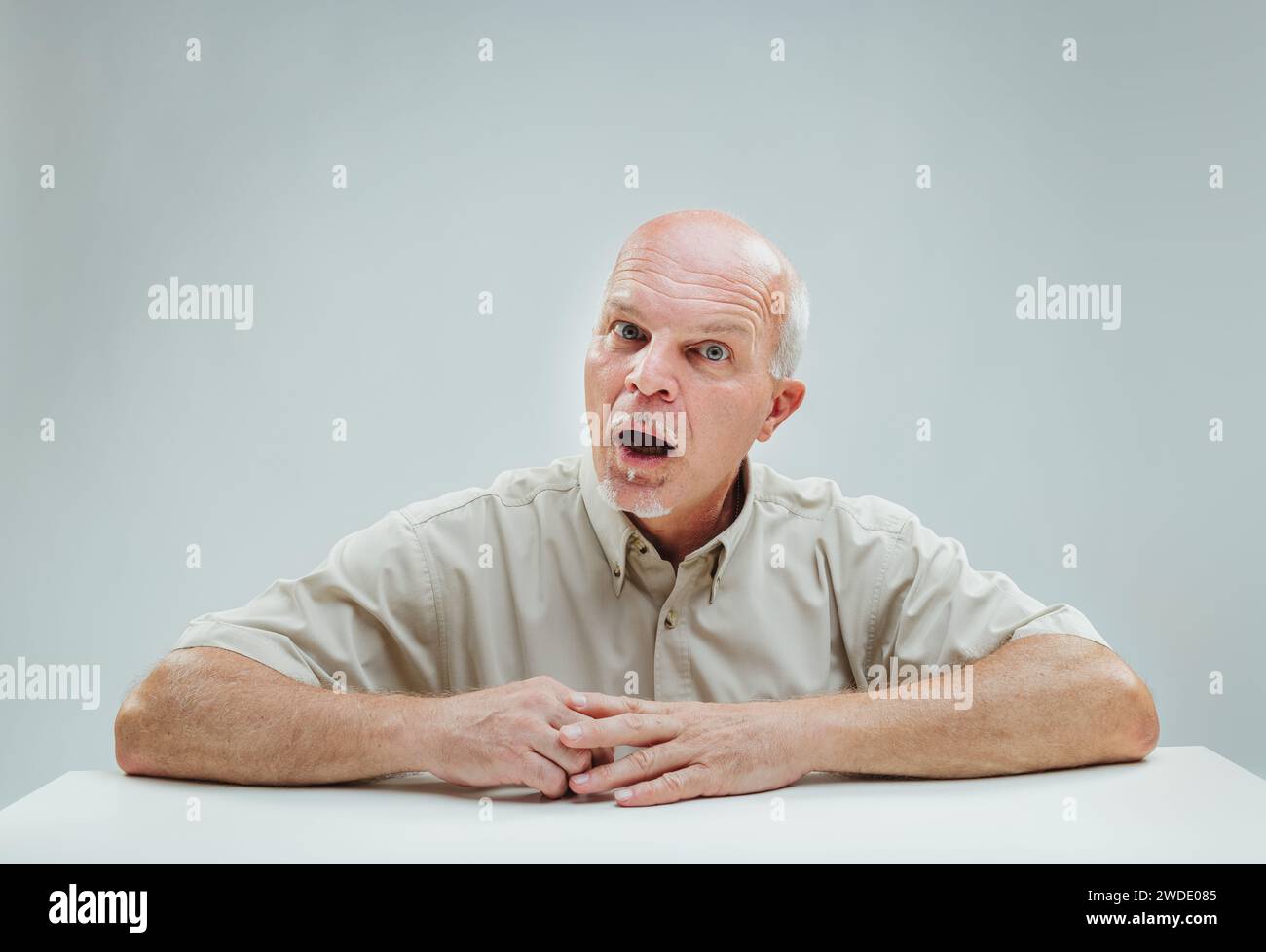 Man at table appears shocked, mouth agape, possibly reacting to an ...
