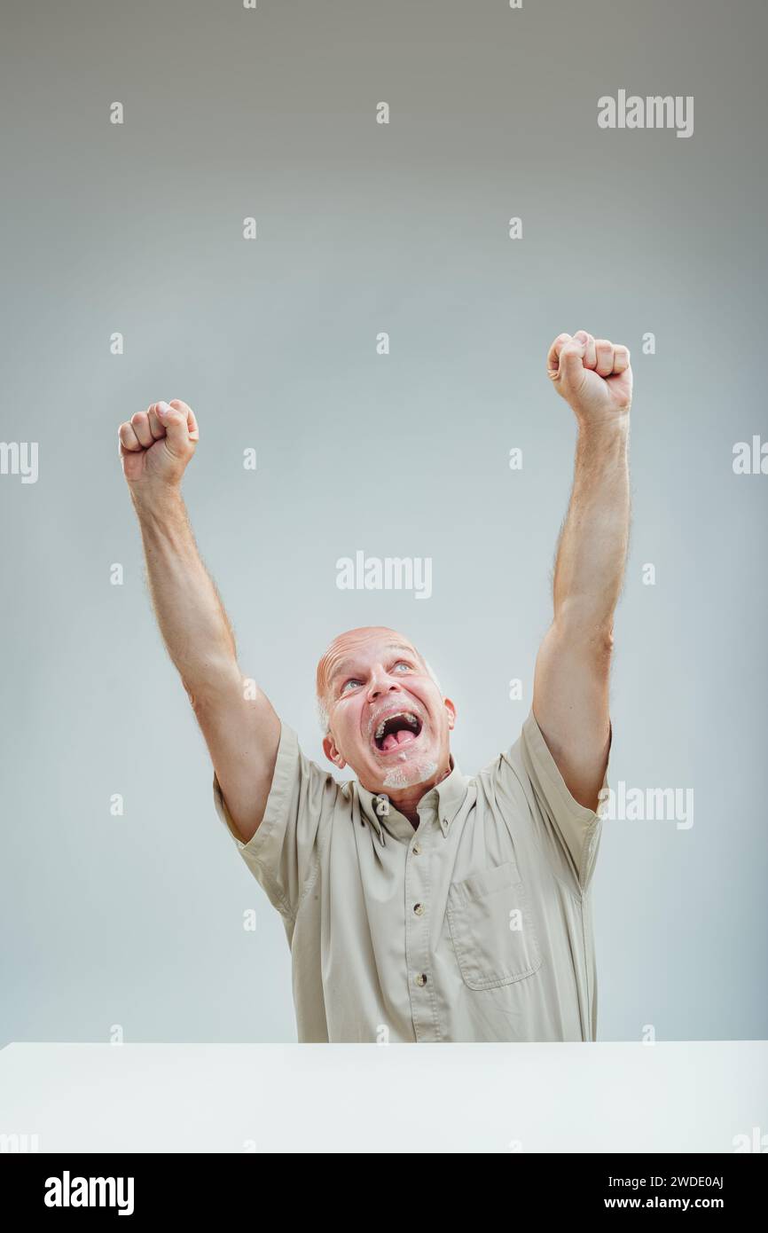 Joyous man celebrates with fists raised high, shouting in triumph at an ...