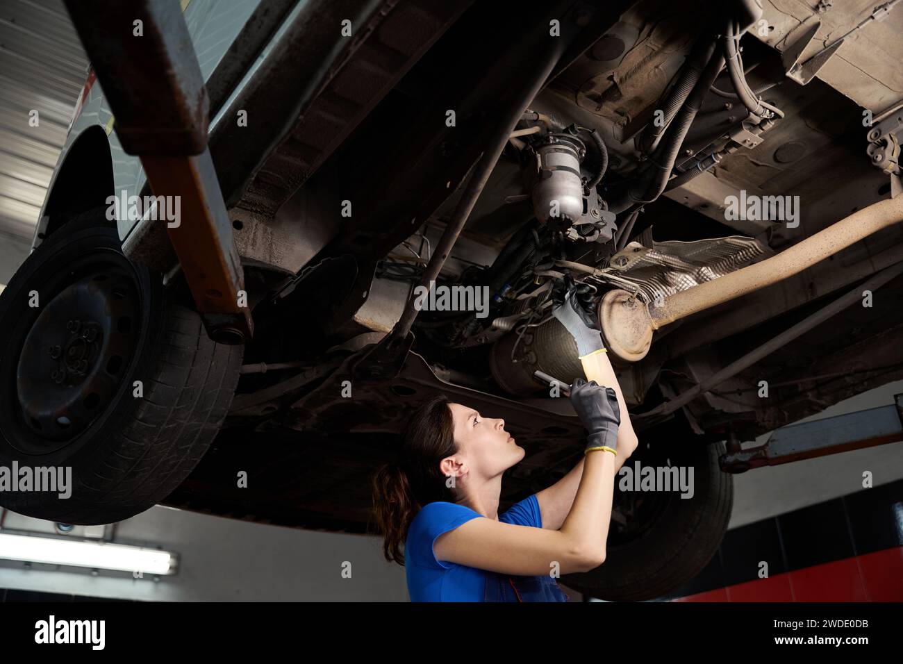 Female inspects chassis of car, raised on a lift Stock Photo - Alamy