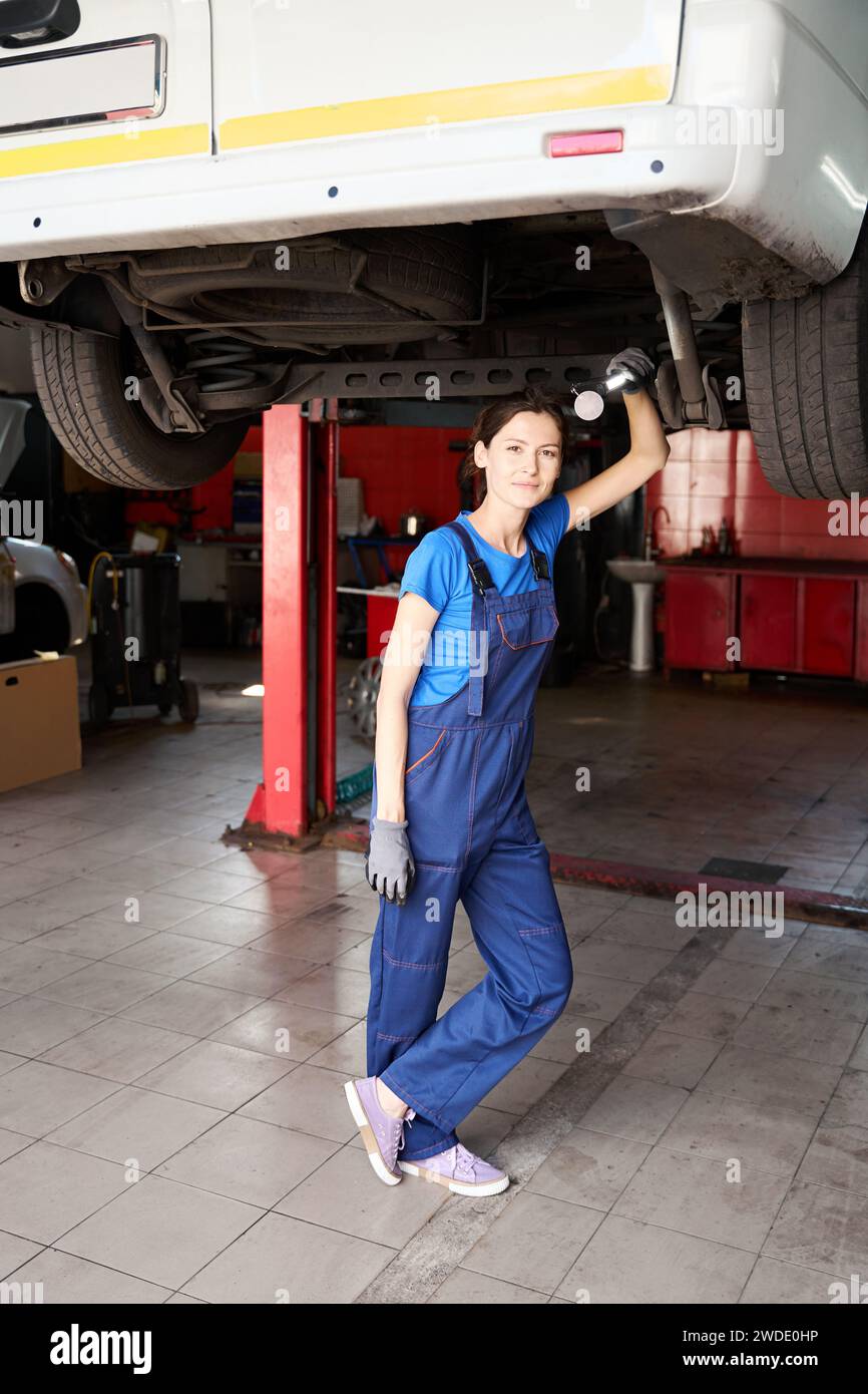 Female auto mechanic stands under a car raised on lift Stock Photo - Alamy
