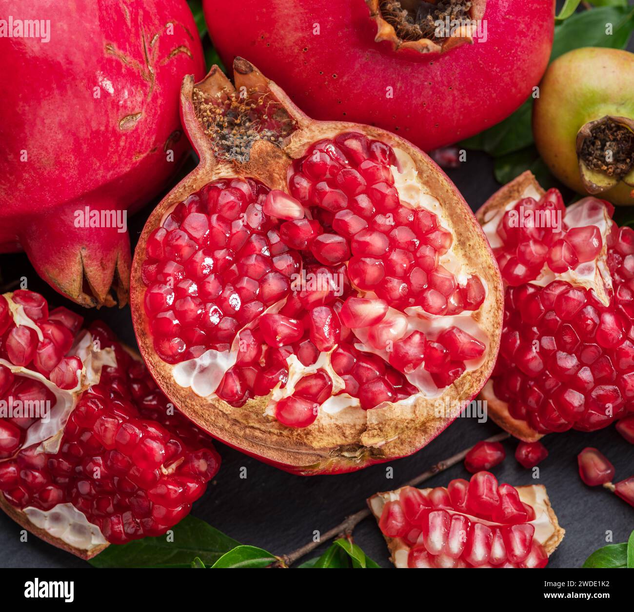 Ripe pomegranate fruits with slices and pomegranate tree leaves on a ...