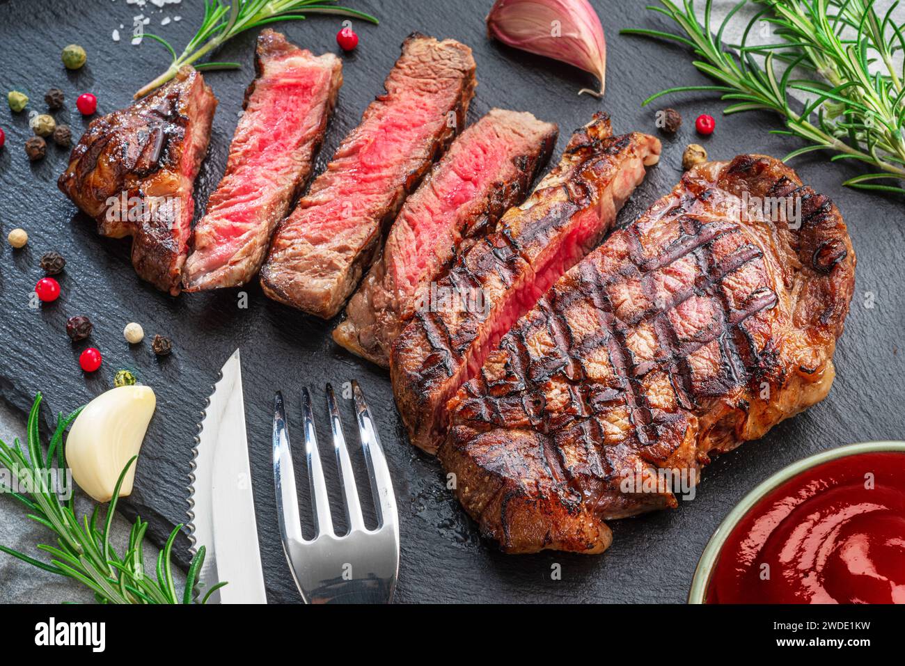 Grilled delicious ribeye steak slices and some seasonings on black ...